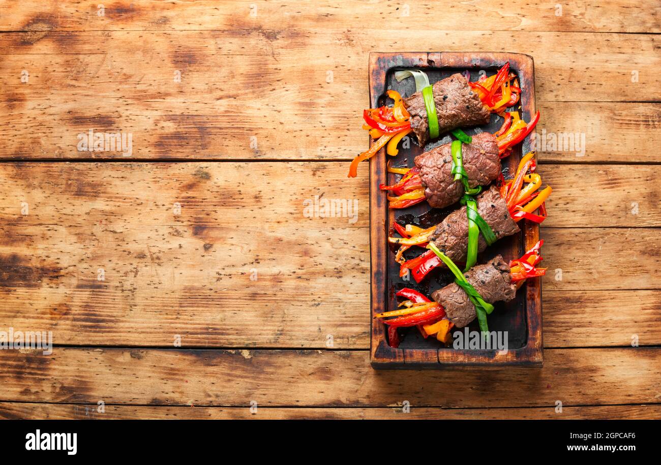 Tasty beef rolls stuffed with bell pepper on rustic wooden table.Space ...