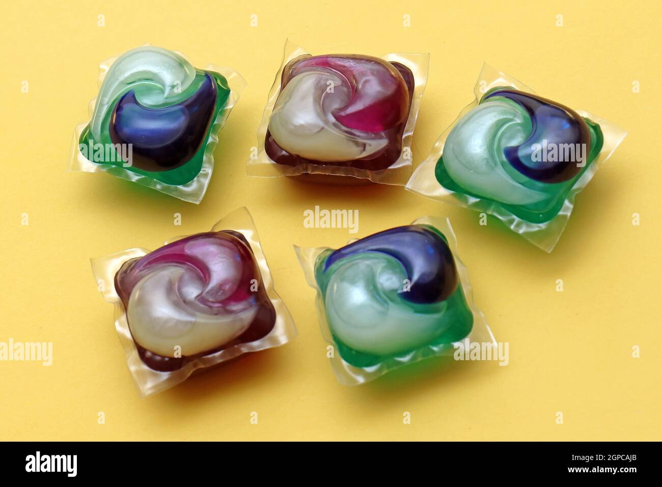 Colorful detergent pods on yellow background used for domestic ...