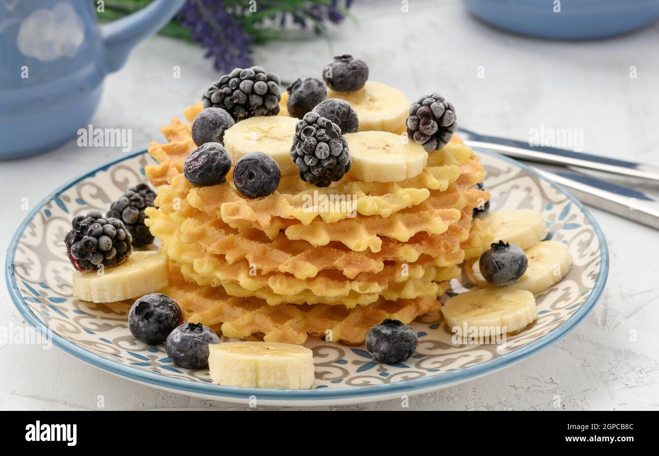 stack of baked Belgian waffles on a round plate with berries on a white ...