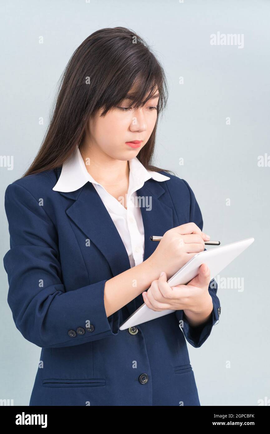 Asian woman in suit using computer digital tablet isolated on gray ...