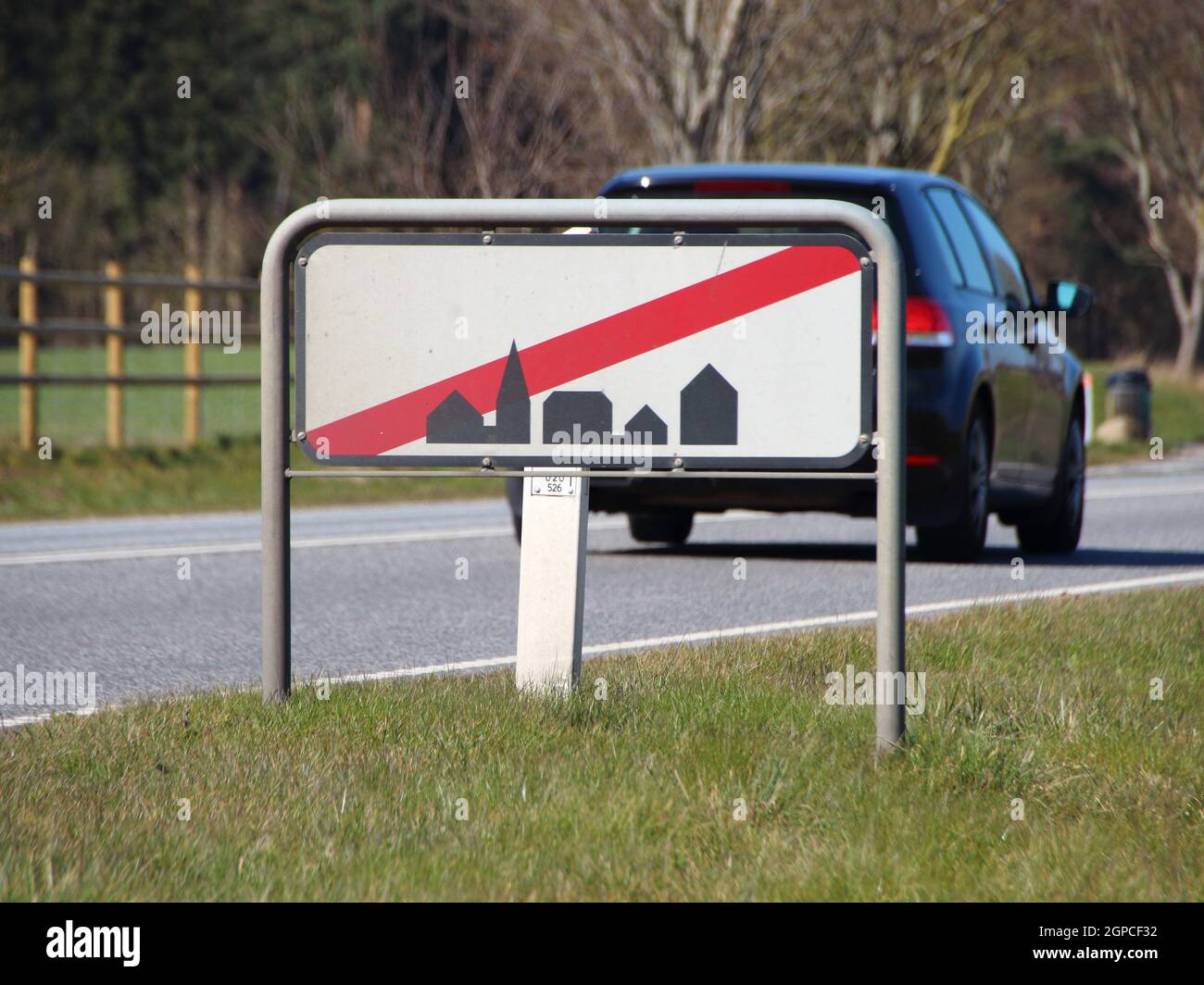 A traffic sign signifying leaving town. A car is directly behind the ...