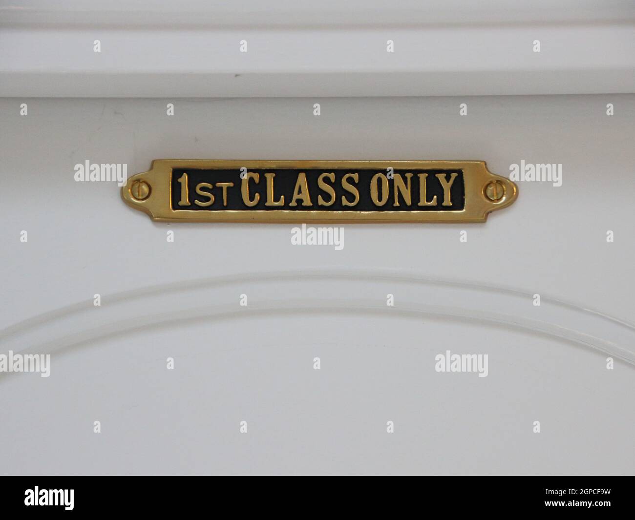 A first class only brass sign on a white door Stock Photo - Alamy