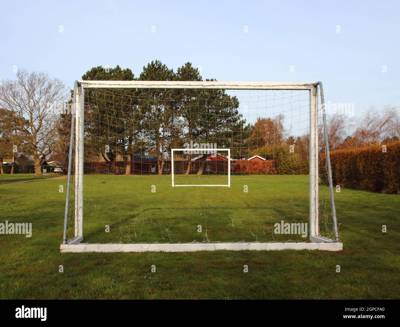 Two white wooden football goal posts on a grassy field, with houses in ...