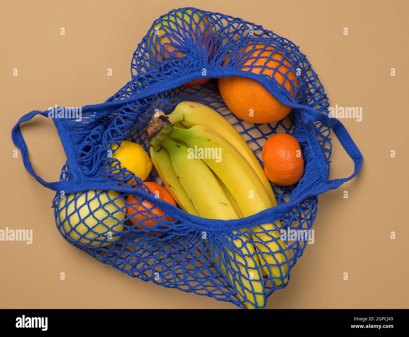 ripe fresh fruits in a textile string bag on a brown background, top ...
