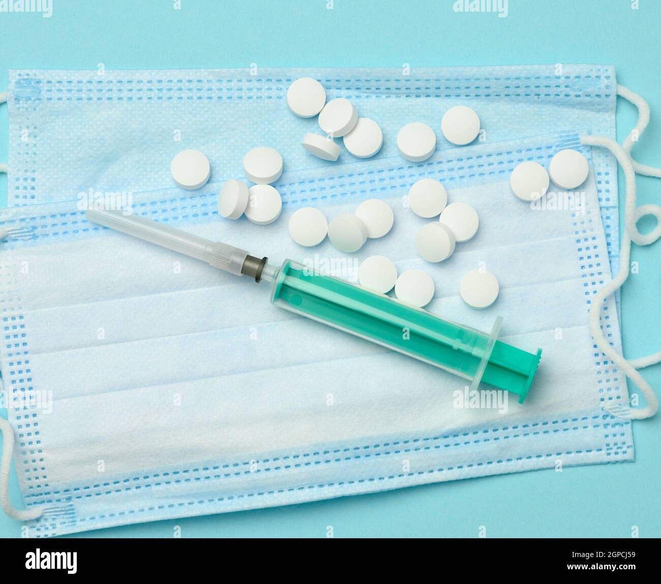round white pills lie on a disposable medical mask, blue background ...