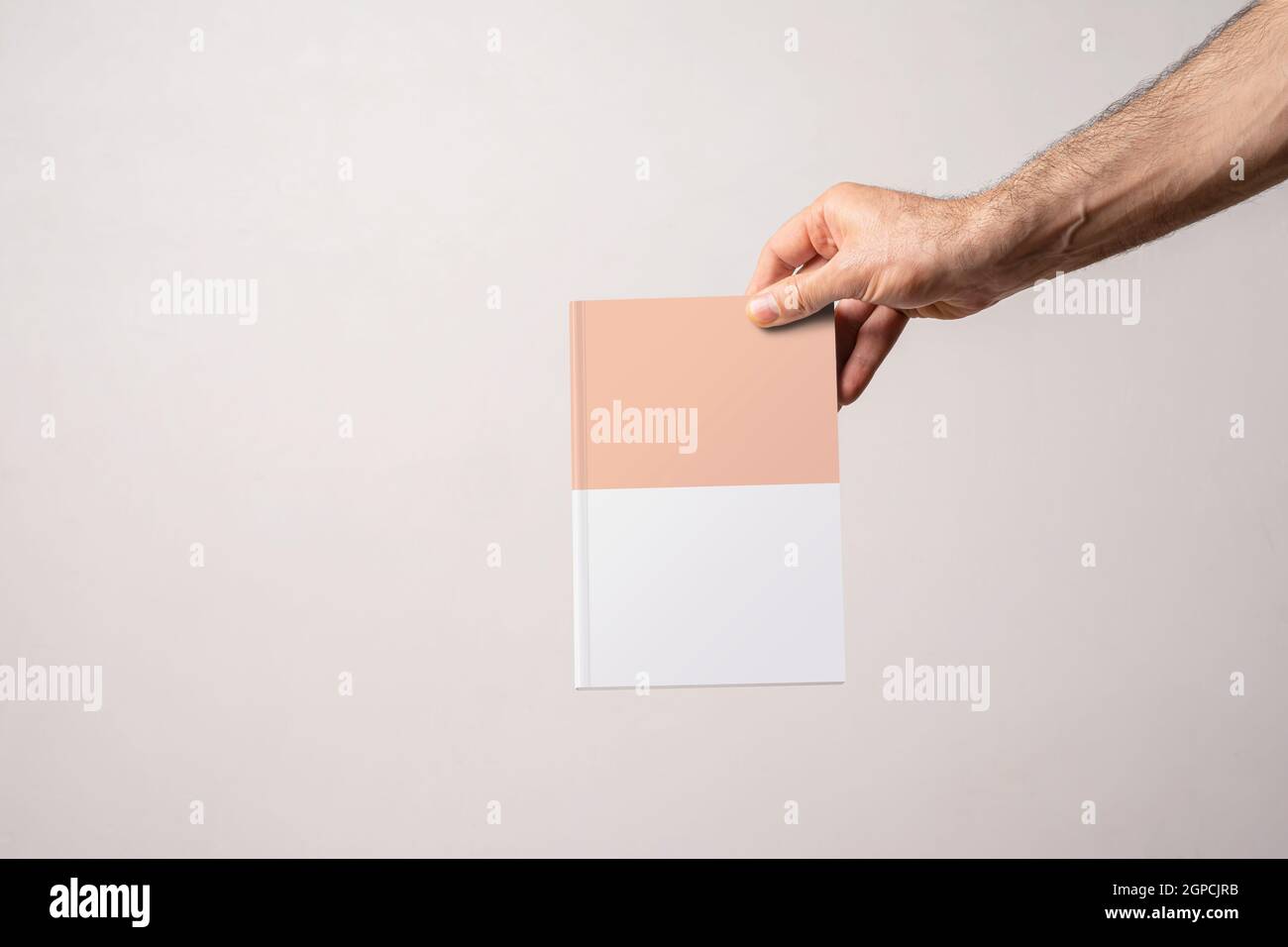 Male hand holding a closed book-catalog with blank cover, editable mock ...