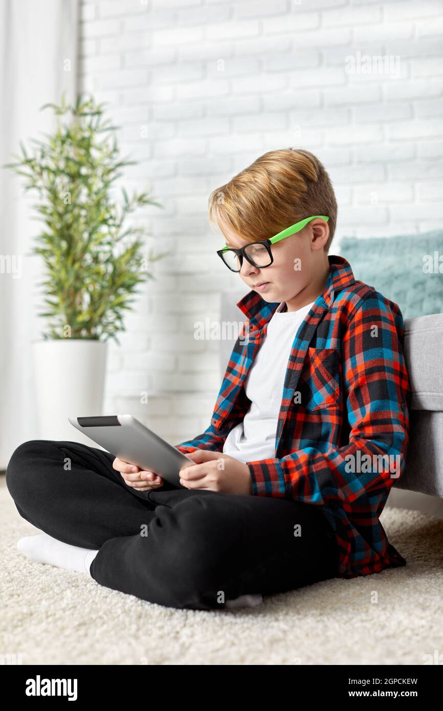 smiling child boy in checkered shirt with digital tablet at home. kid ...