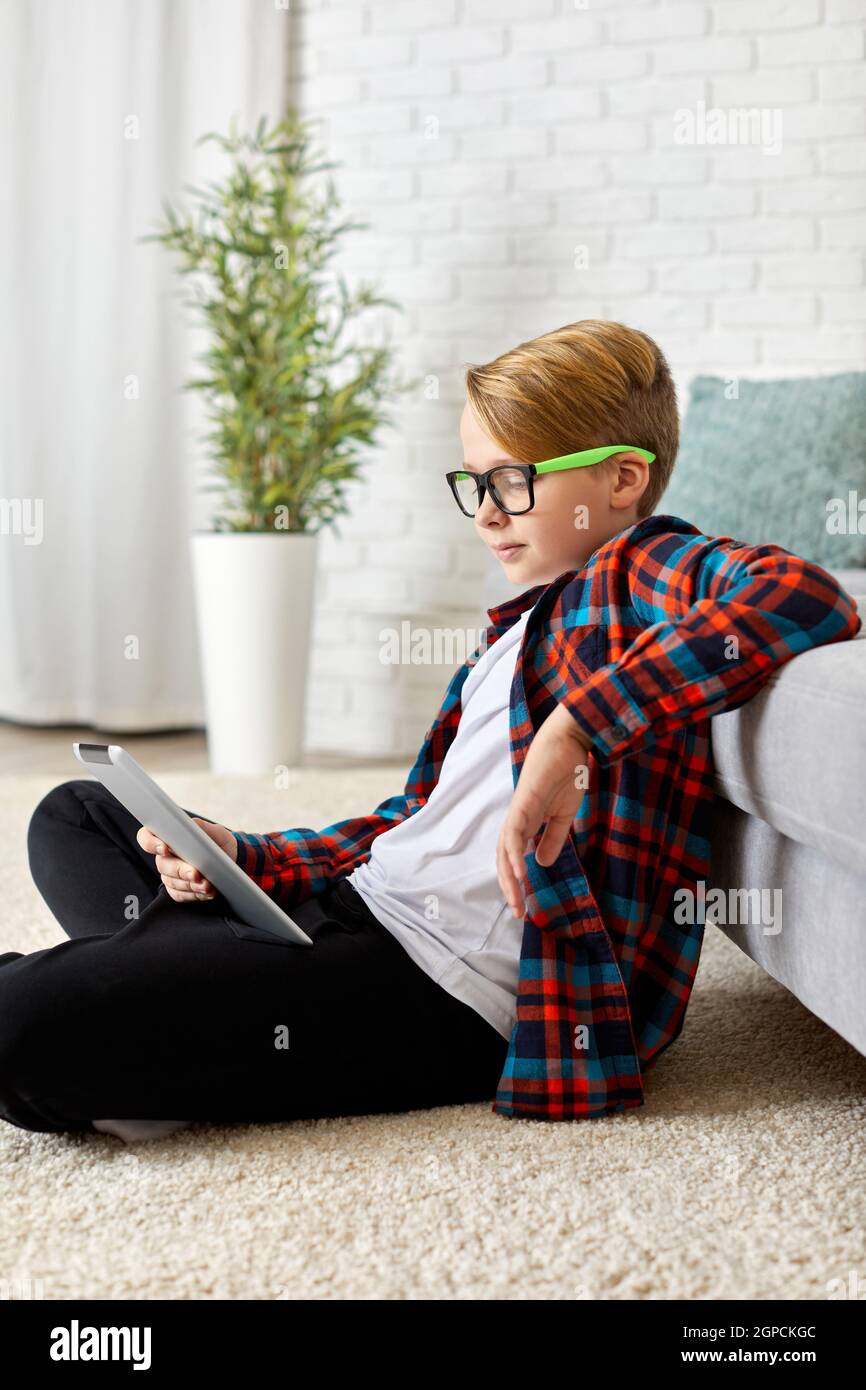 smiling child boy in checkered shirt with digital tablet at home. kid ...