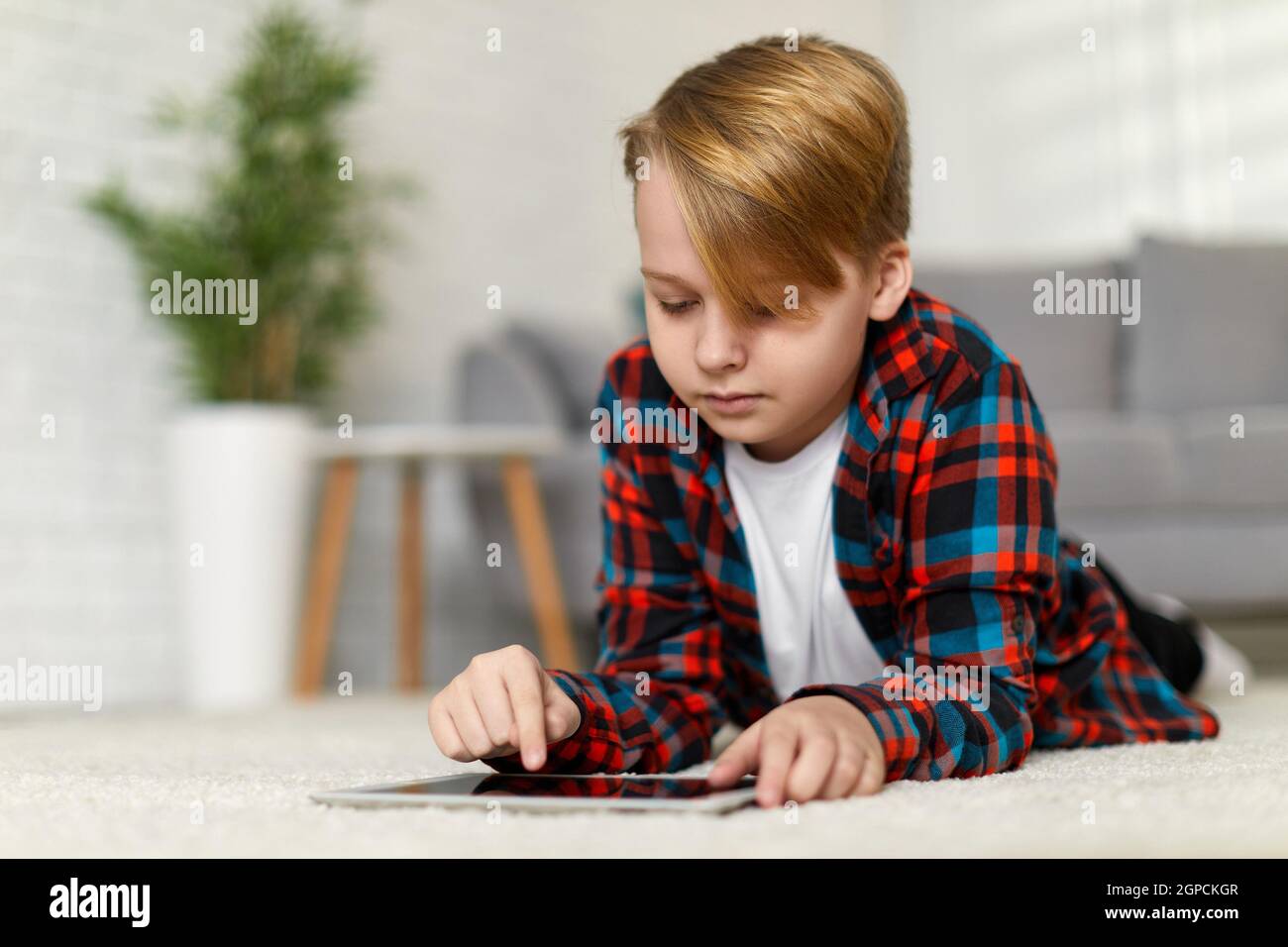 caucasian child boy in checkered shirt lies on floor and looks at the ...