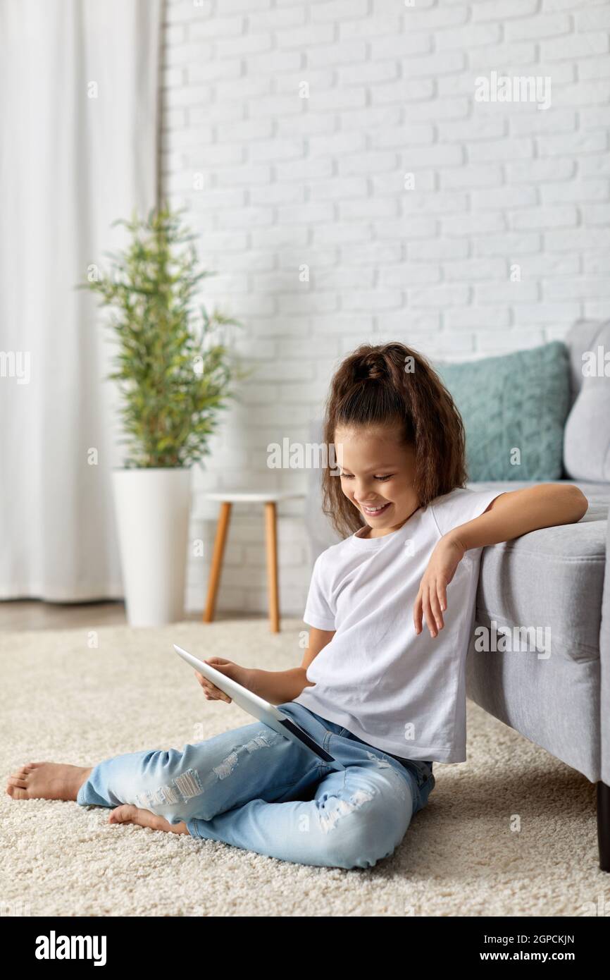 smiling little child girl using digital tablet at home. kid using ...