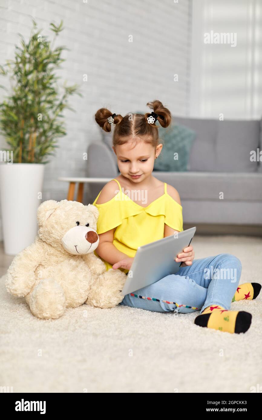 cute little child girl with teddy bear using digital tablet. kid ...