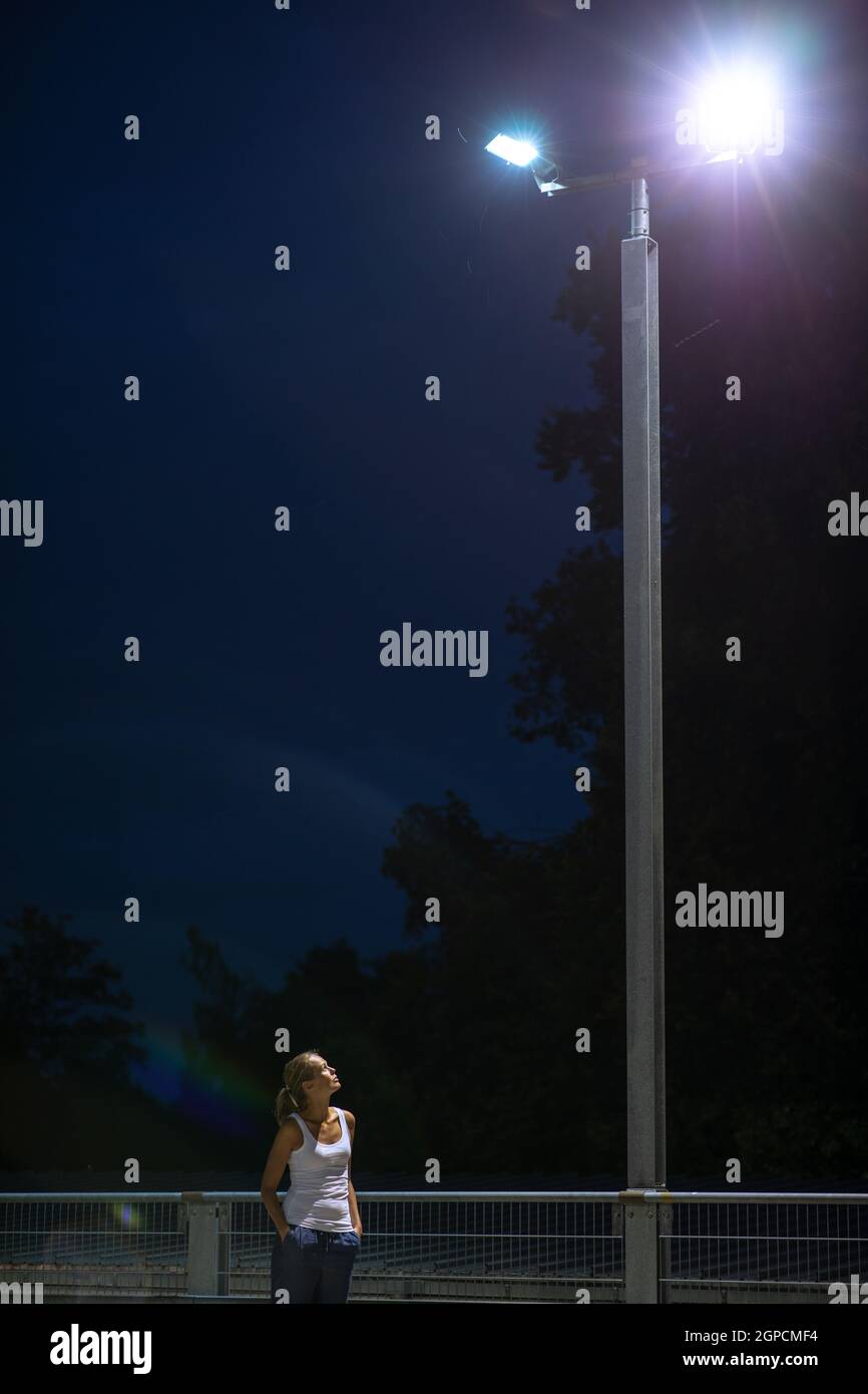 Young woman disturbed by harmful, cold, blue light of LED light in an ...