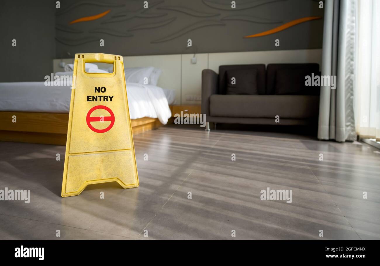 A yellow "NO ENTRY" sign place on the floor in hotel room. While ...