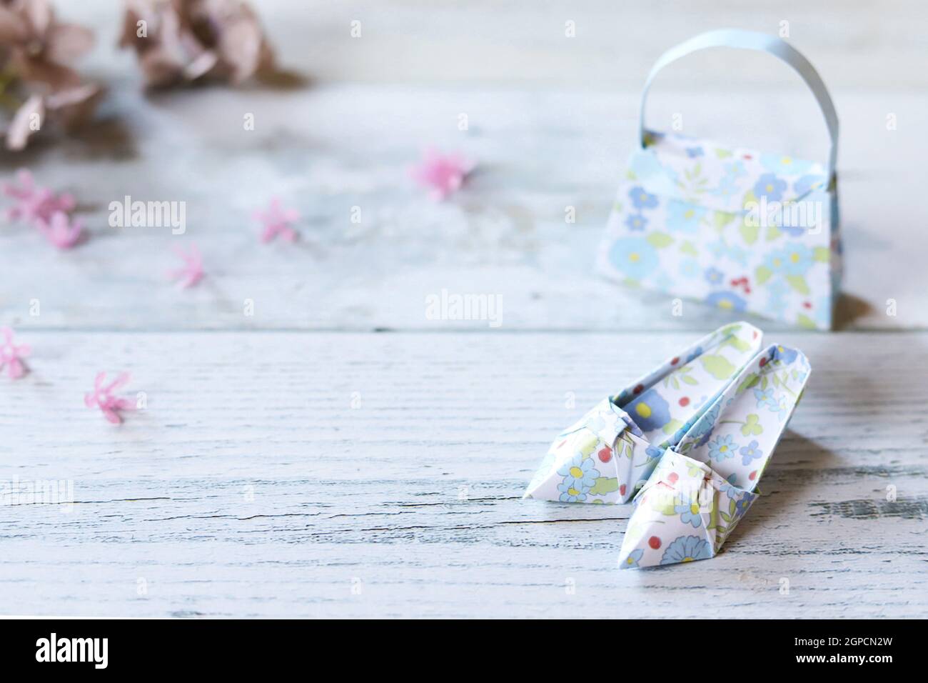 Origami high heels and a handbag on the white painted wooden table ...