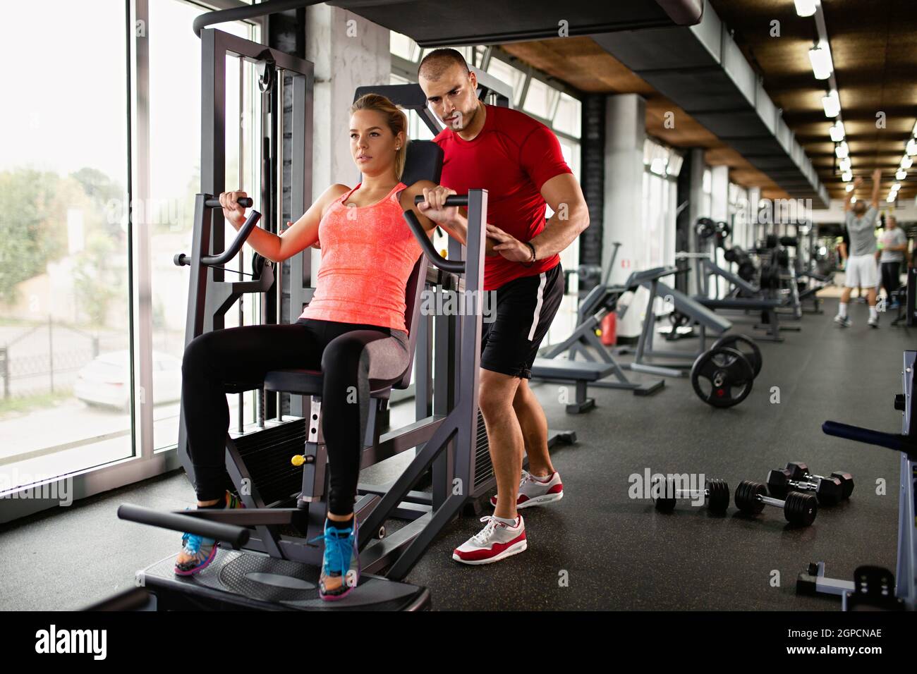 Personal trainer helping a woman to working out in gym. Sport people ...
