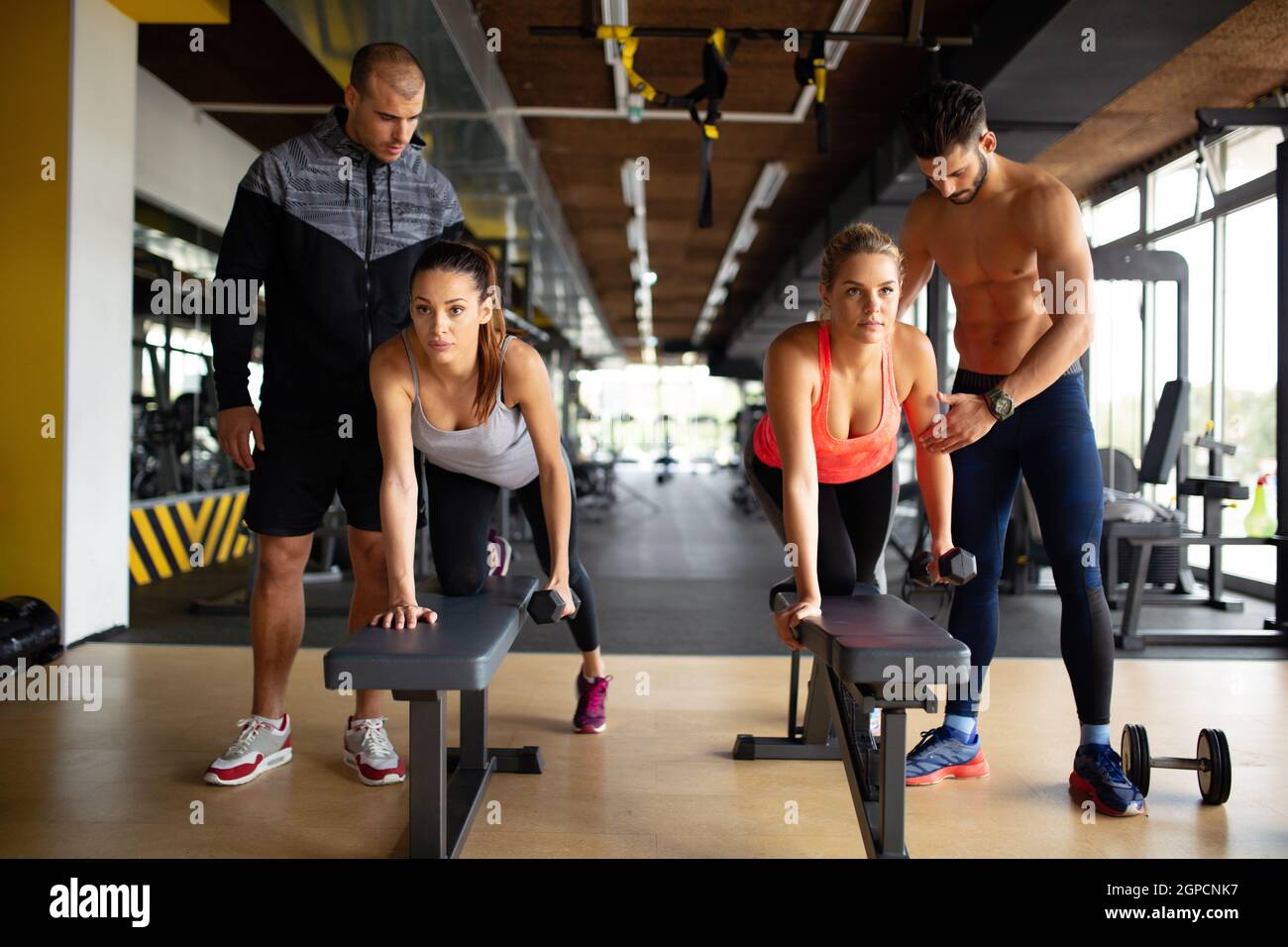 Group of athletic young people in sportswear with dumbbells exercising ...