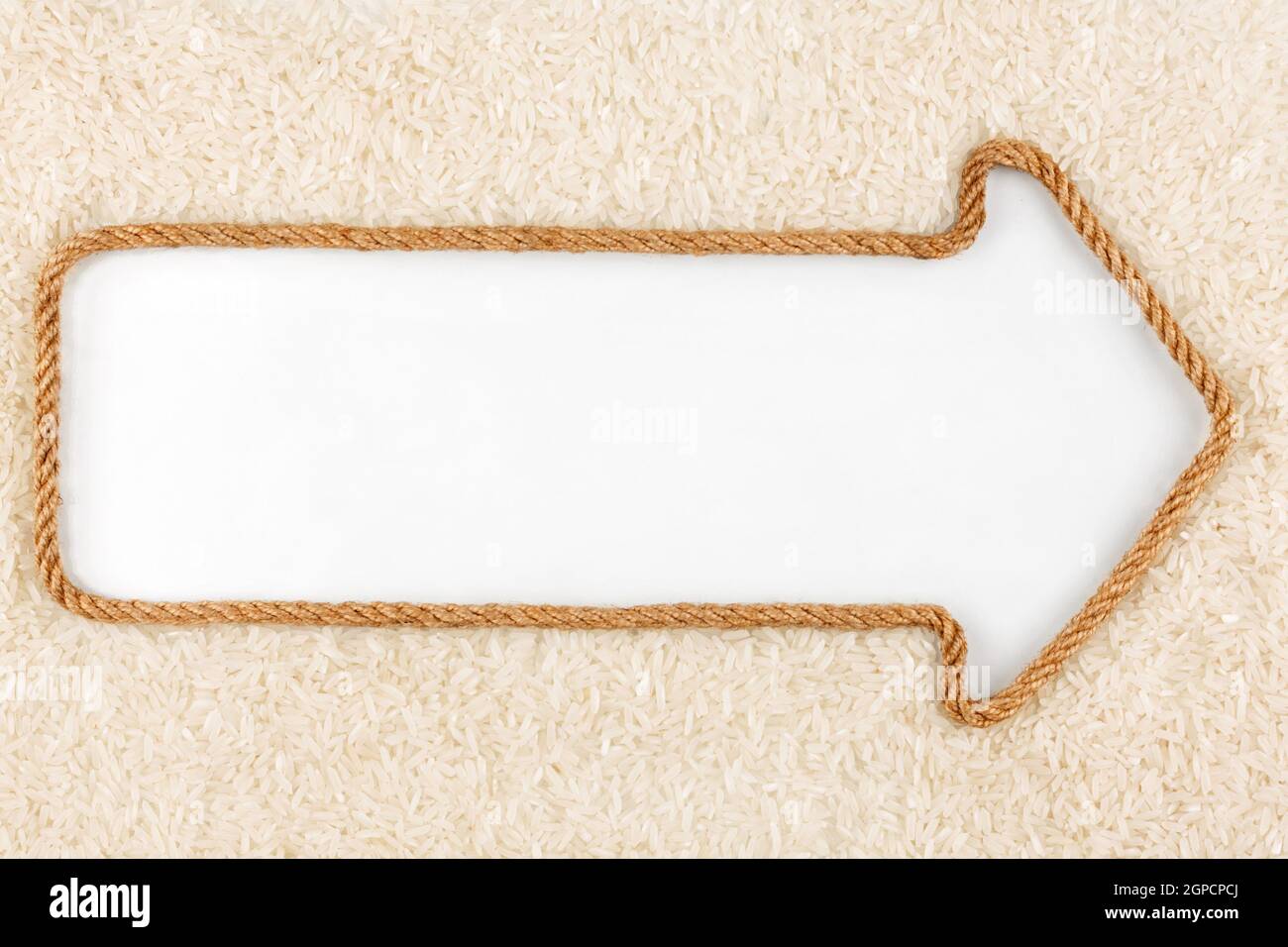 Arrow made of rope and rice with a white background, with place for ...