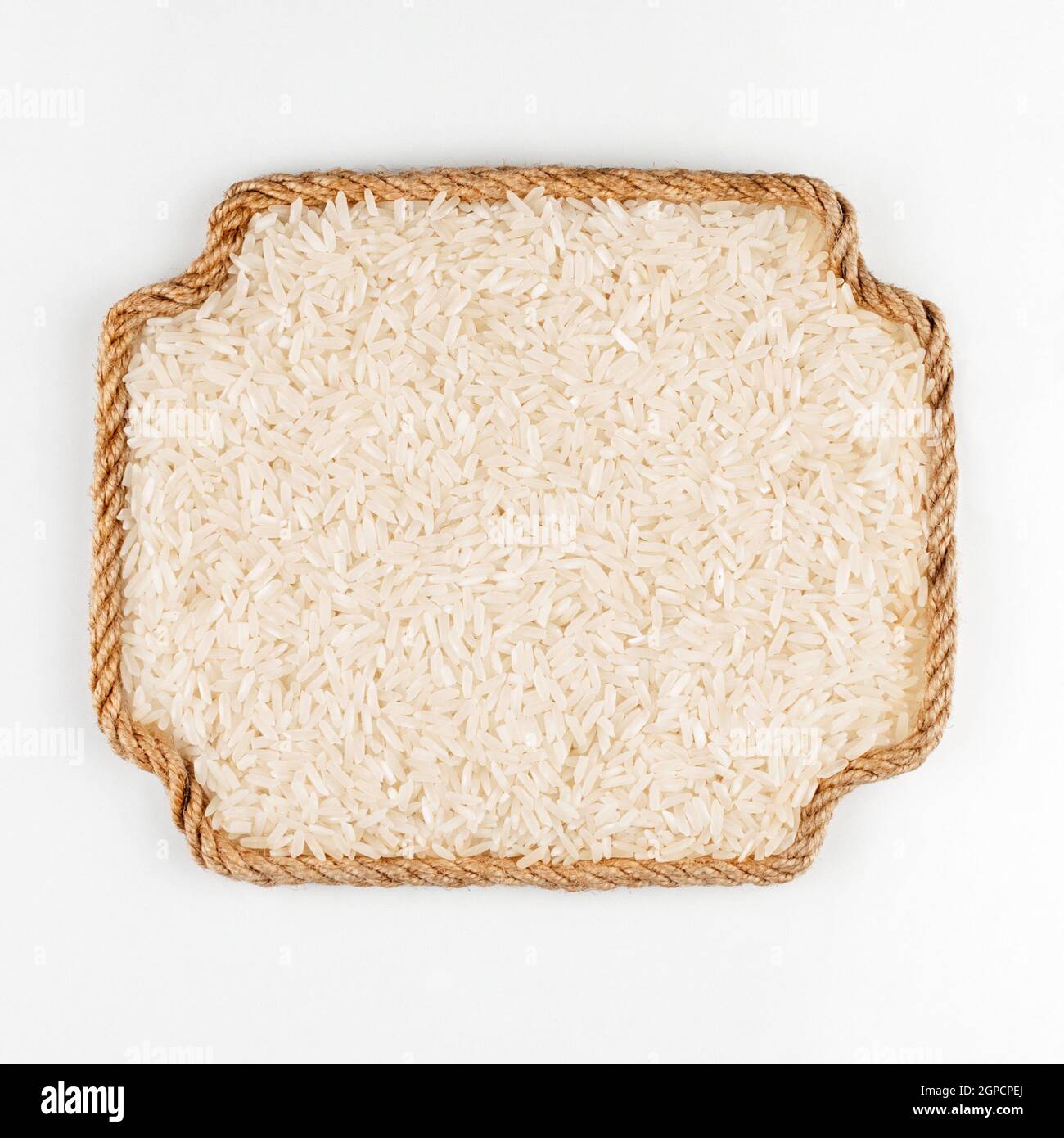 Frame made of rope with rice lying on a white background, with place ...