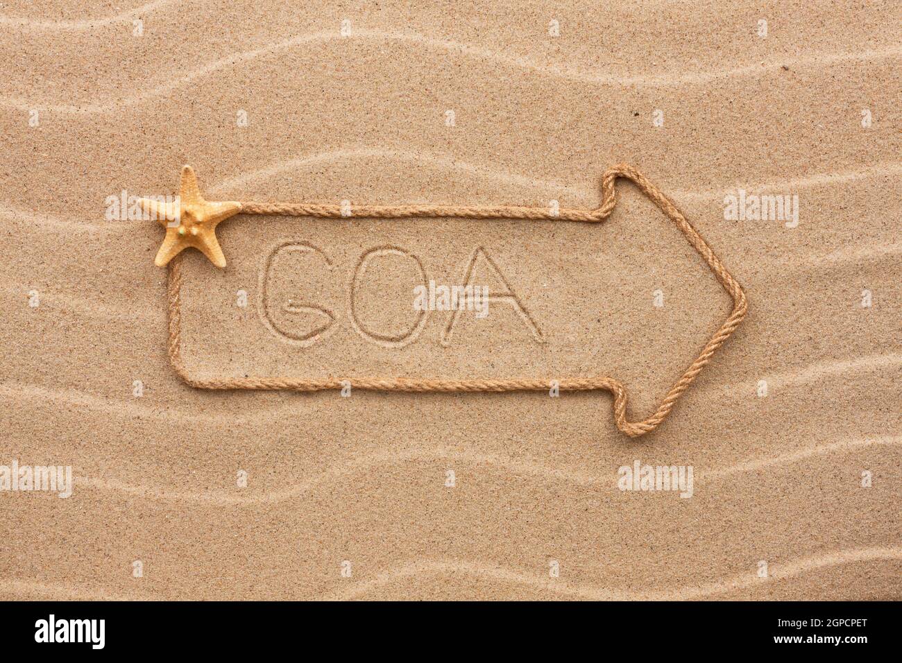 Arrow made of rope and sea shells with the word Goa on the sand, as ...