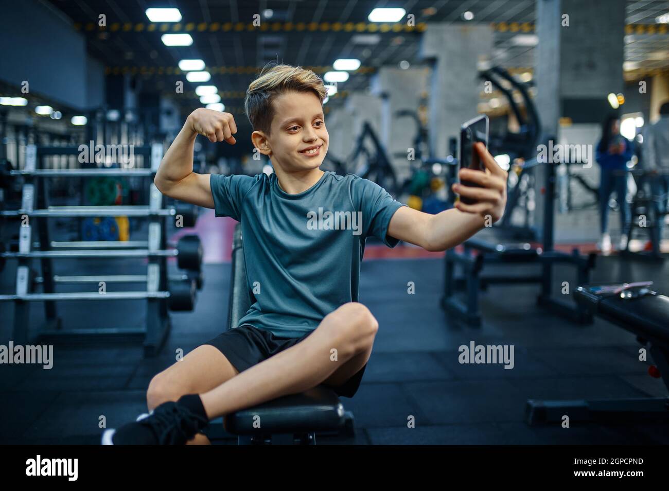 Boy with phone makes selfie on bench in gym. Youngster on training in ...
