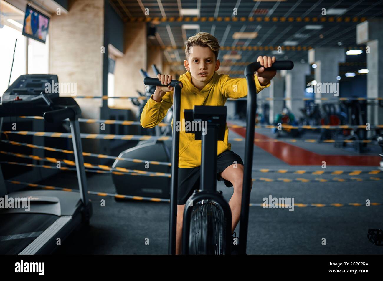 Child on exercise machine, side view, training in gym. Youngster in ...