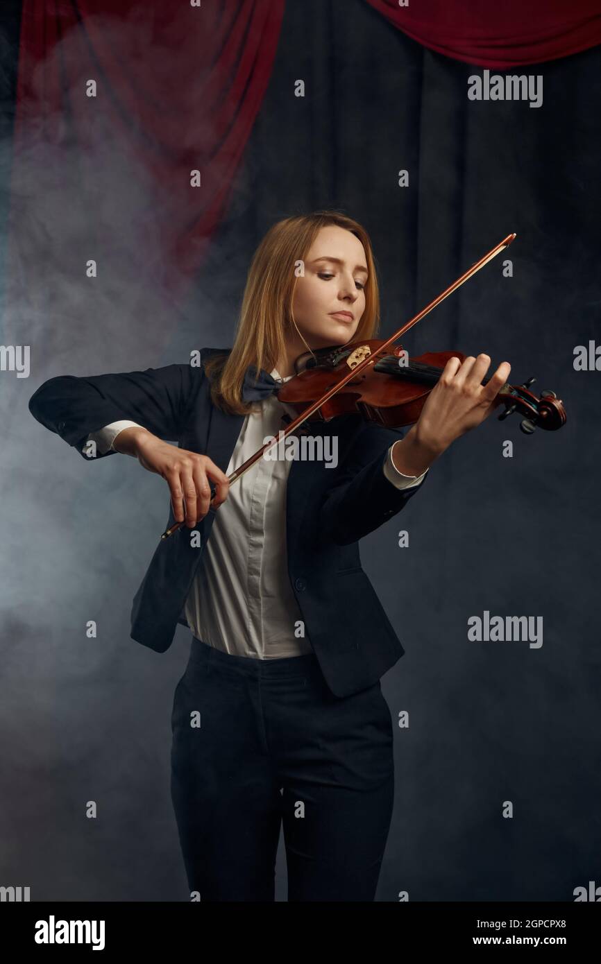 Female violonist with bow and violin, performance on stage. Woman with ...
