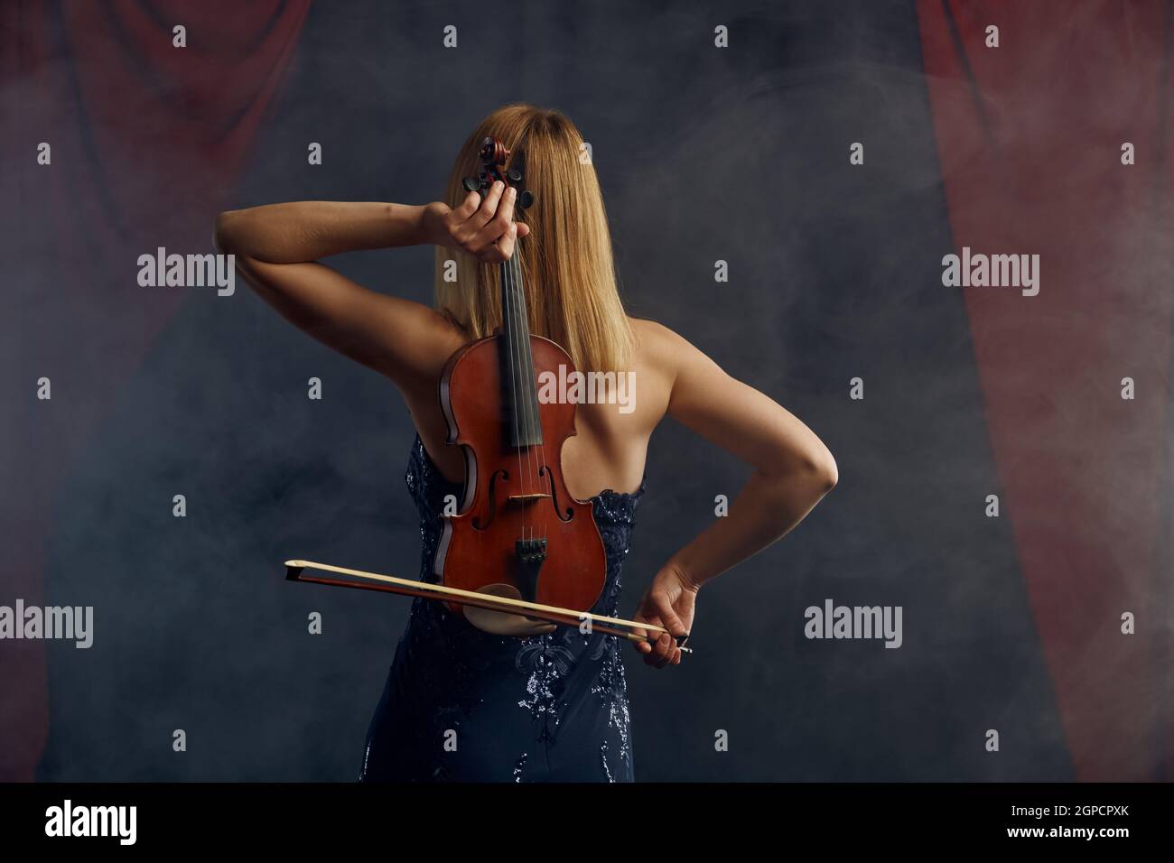 Female violonist with bow and violin behind her back, virtuoso ...