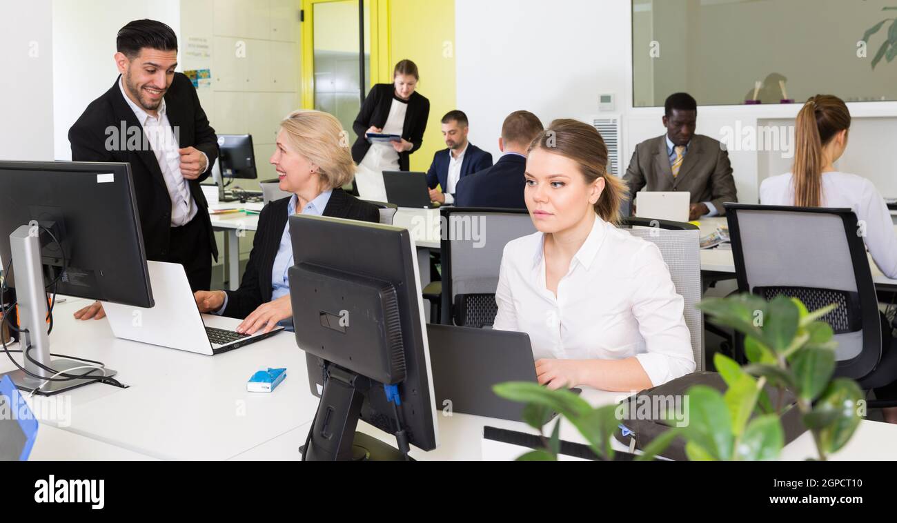 Coworkers engaged in open plan office Stock Photo - Alamy