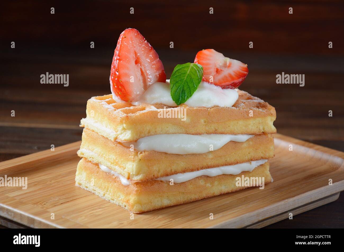 Belgian waffles with strawberries, whipped cream and mint leaves. Tasty ...