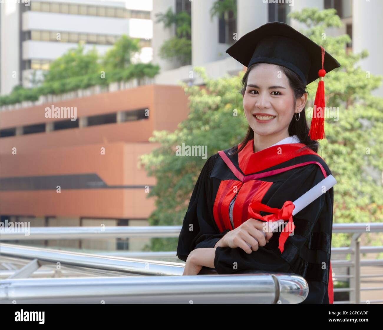 Portrait of happy graduated woman in black graduation gowns holding ...
