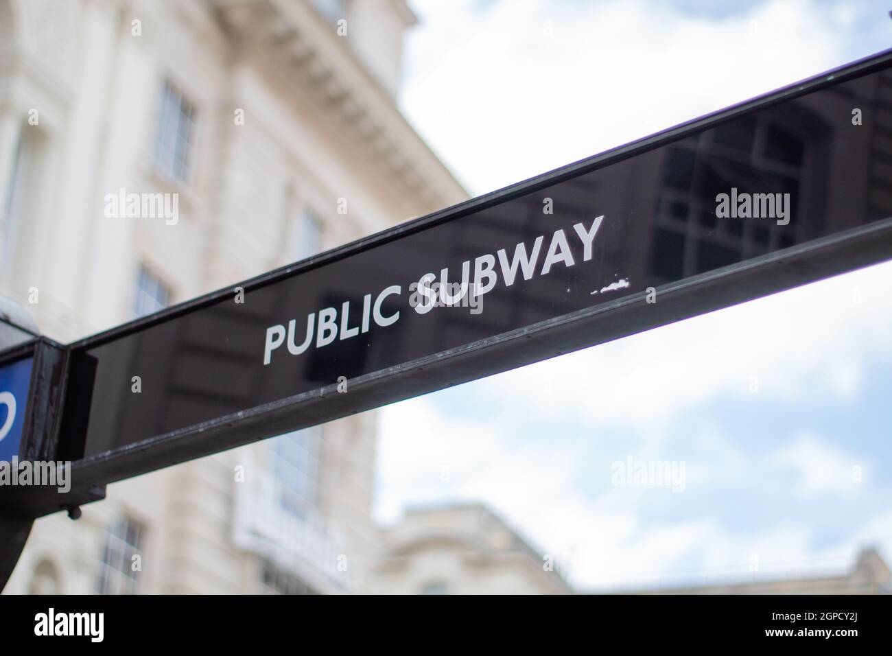 Black public subway sign with blurry classic building as background ...
