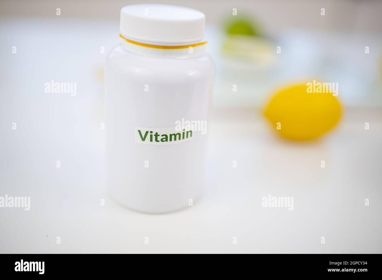 Bottle of vitamins on white table with blurry limes and lemons as ...