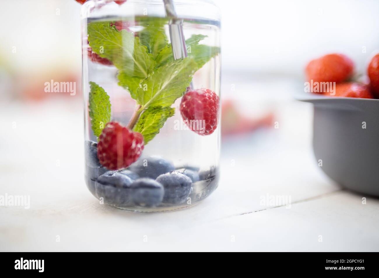 Raspberries, blueberries, and mint floating inside a jar. Beverage ...