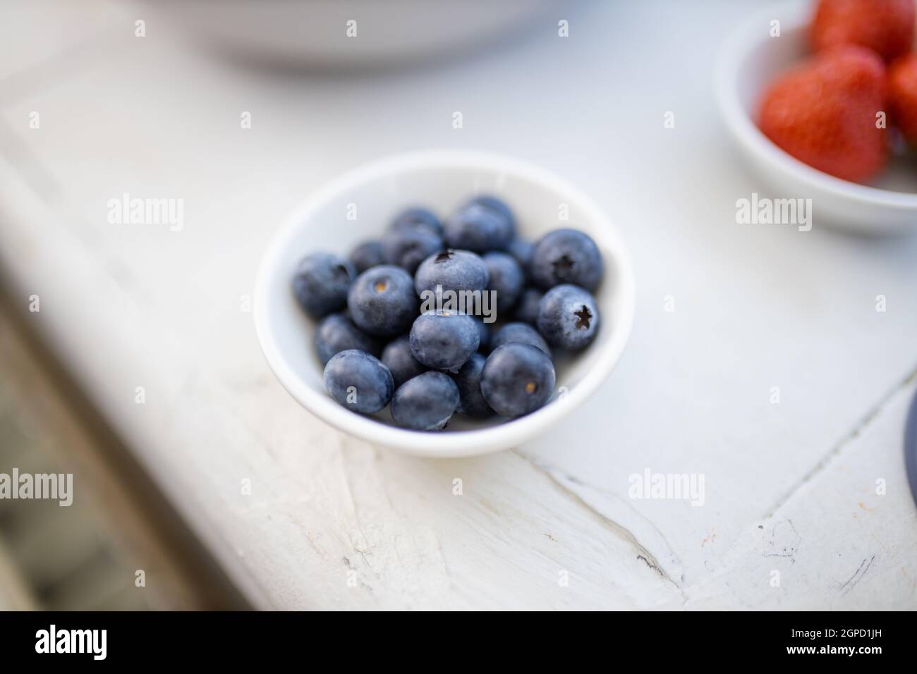 Small plates of blueberries and strawberries on white table. Fresh ...