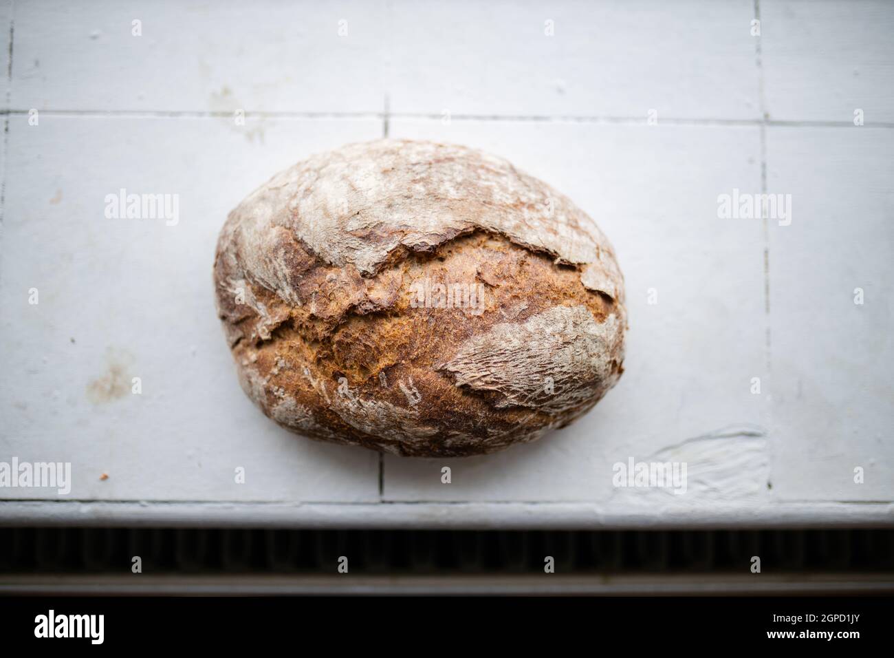 Fresh sourdough bread on white tiled kitchen counter from above. Tasty ...