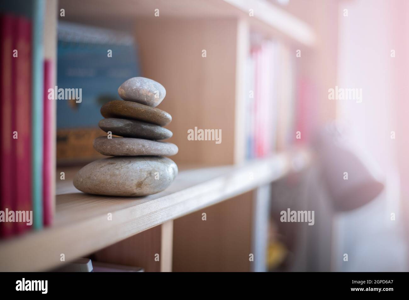 Feng Shui: Stone cairn at home in a book shelf, blurry books in ...