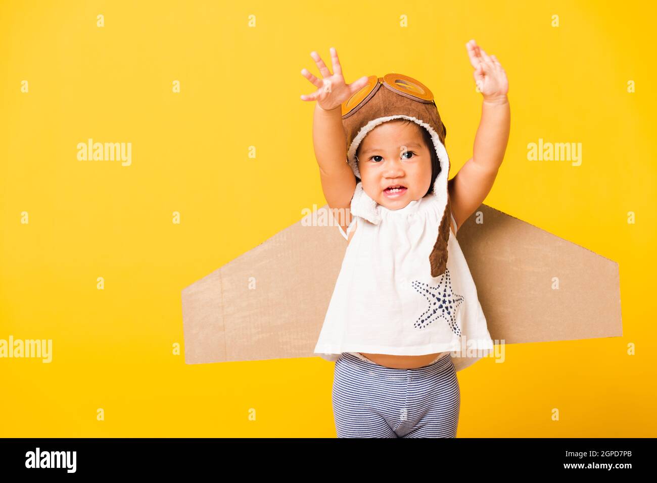 Happy Asian beautiful funny baby little girl smile wear pilot hat raise ...