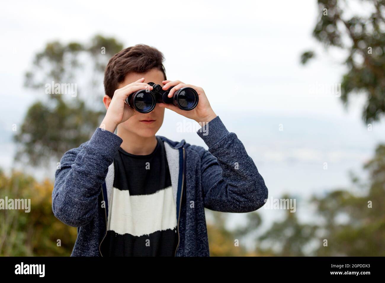 Teenager guy looking with binoculars in the nature Stock Photo - Alamy