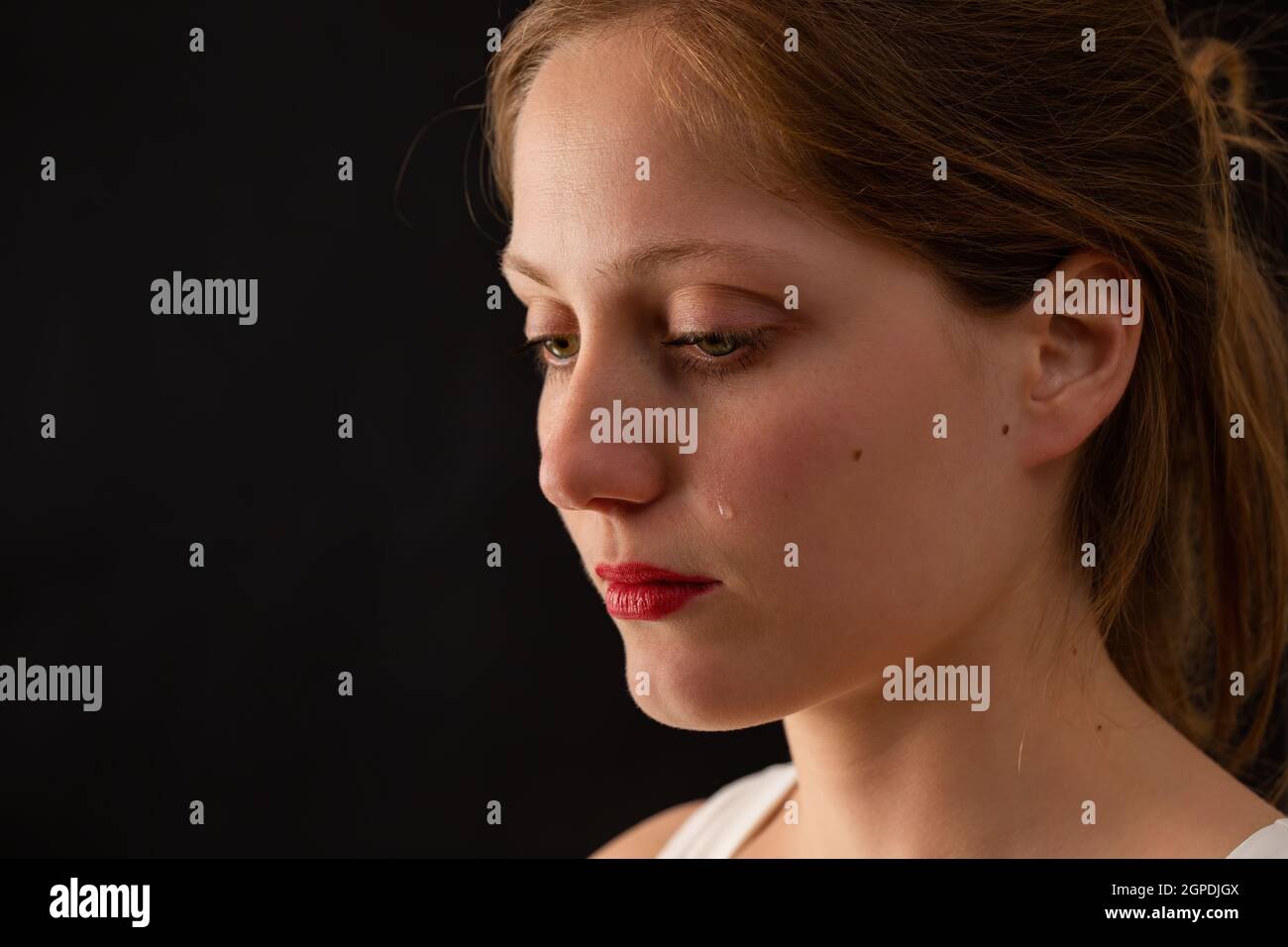 Crying blonde woman looking down on dark background. Depressed female ...