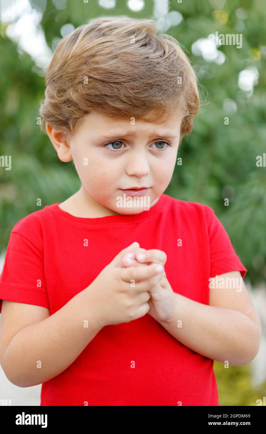 Sad child with red t-shirt in the garden Stock Photo - Alamy
