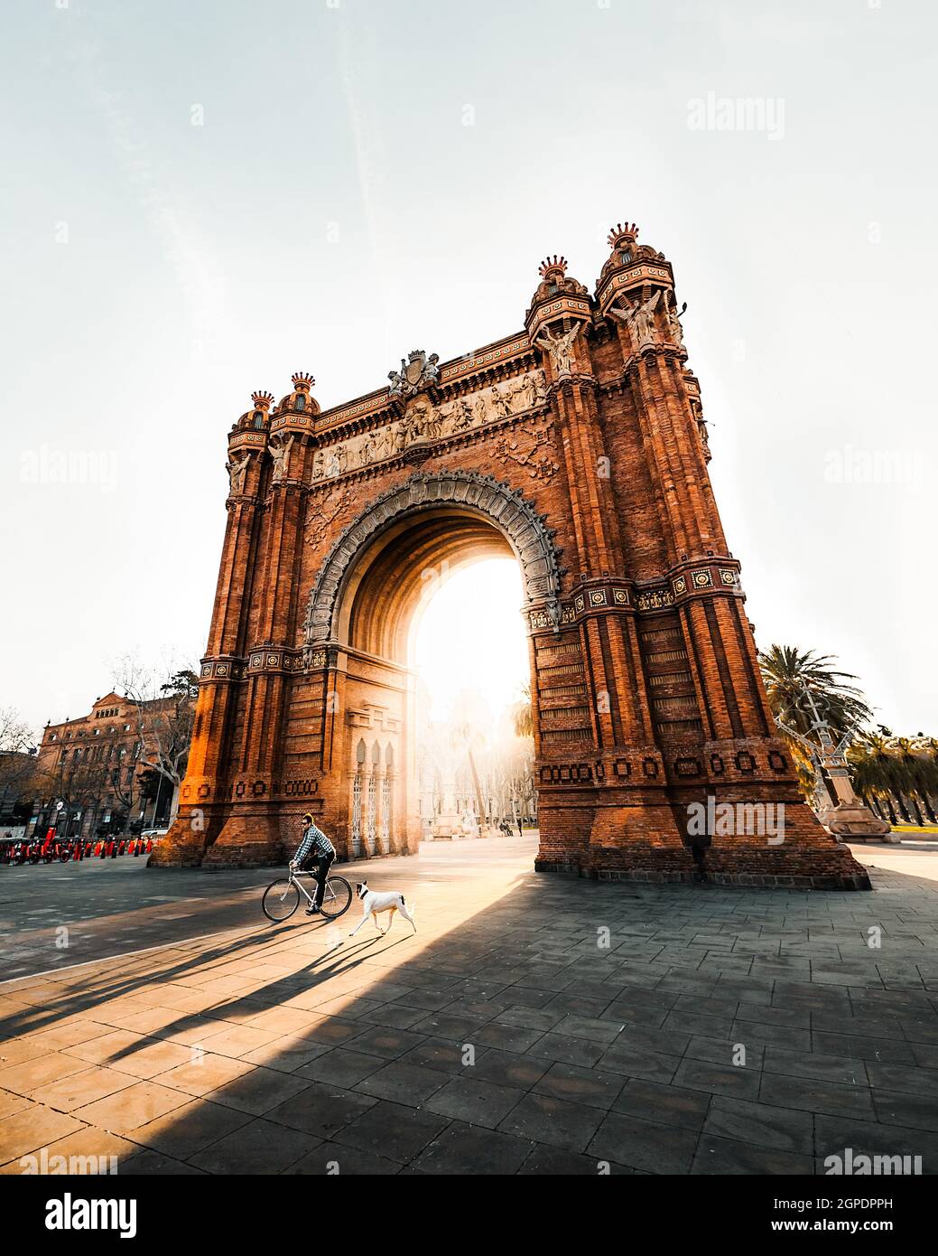 BARCELONA, SPAIN - Sep 09, 2021: A person riding a bike and a dog passing by the Arc de Triomf ...