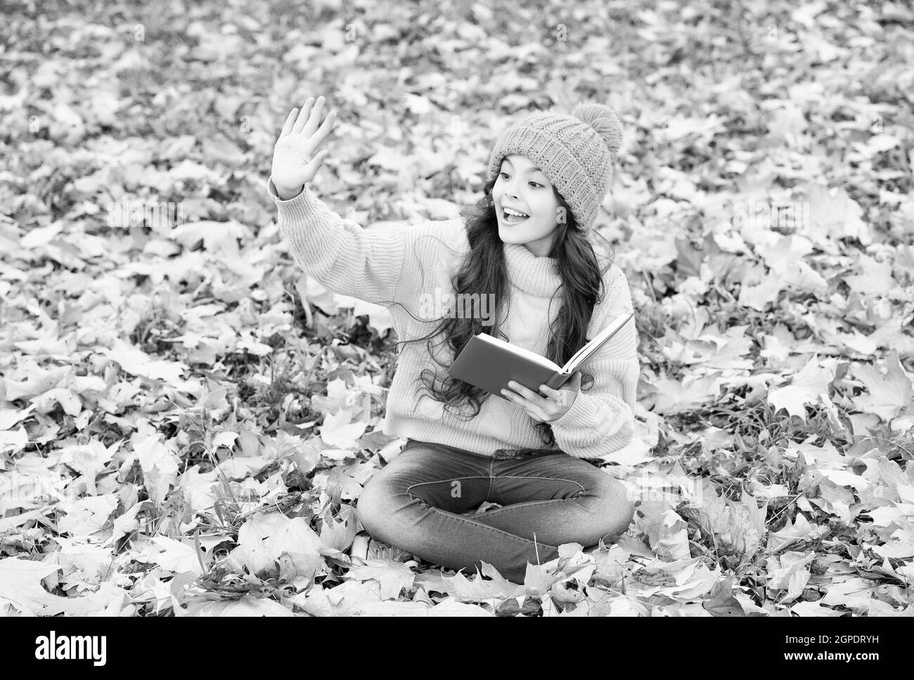 Hello school. Happy kid give salute reading book on autumn leaves ...