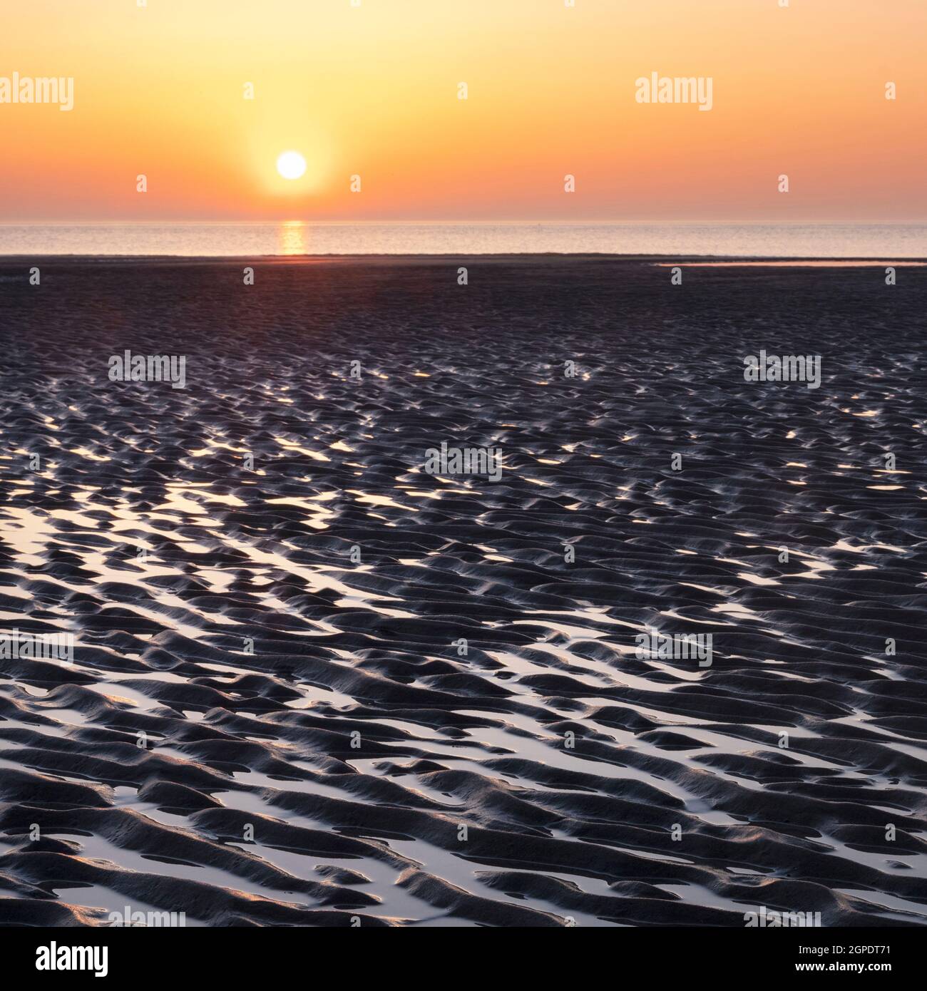 pattern in sand and colorful reflection of setting sun in water Stock ...