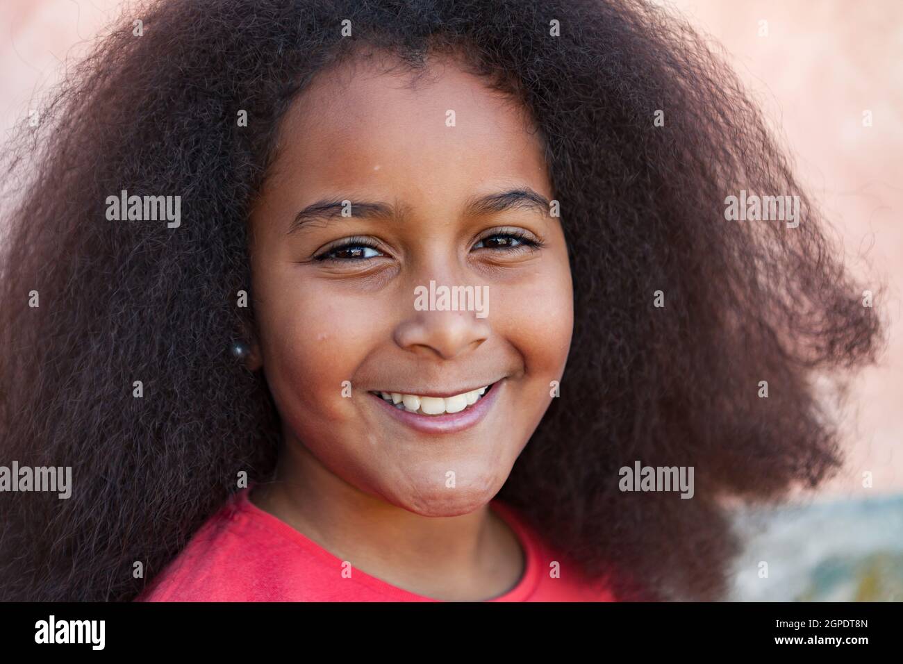 Pretty girl with long afro hair in the garden laughing Stock Photo - Alamy