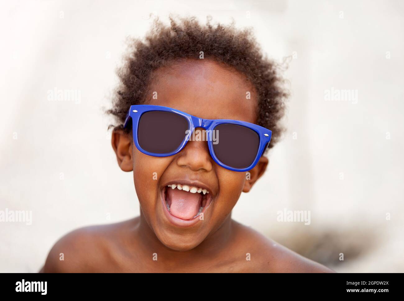 Funny Afro-American kid with blue sunglasses and a beautiful smile ...