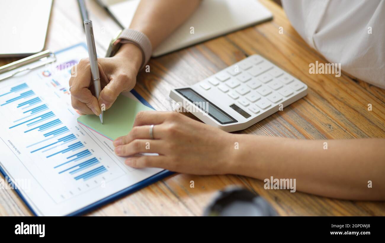 Cropped image of female worker or business women taking notes on sticky ...