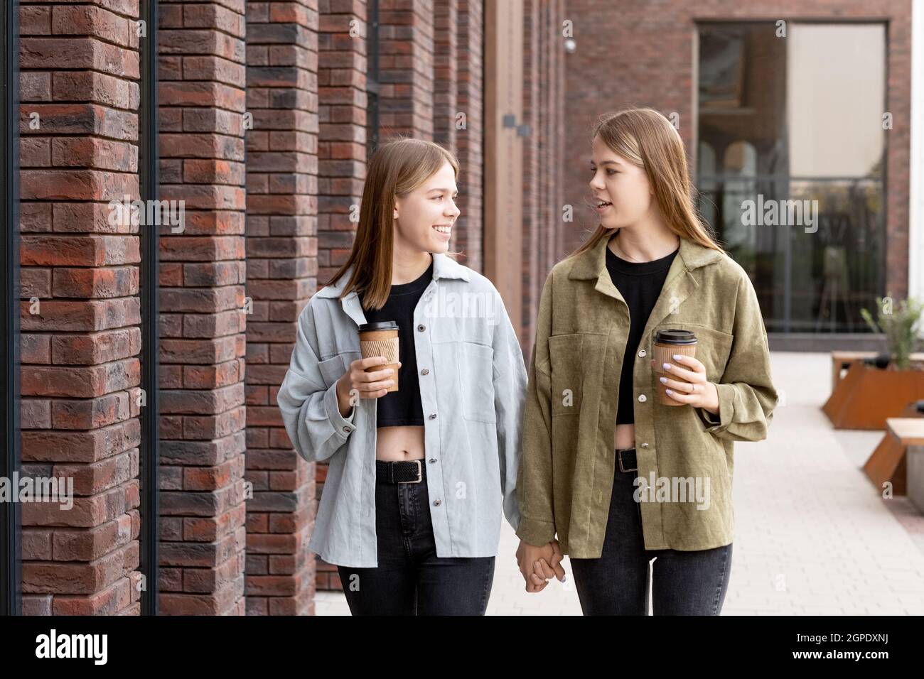 Twin girls interacting and having drinks while moving along modern ...