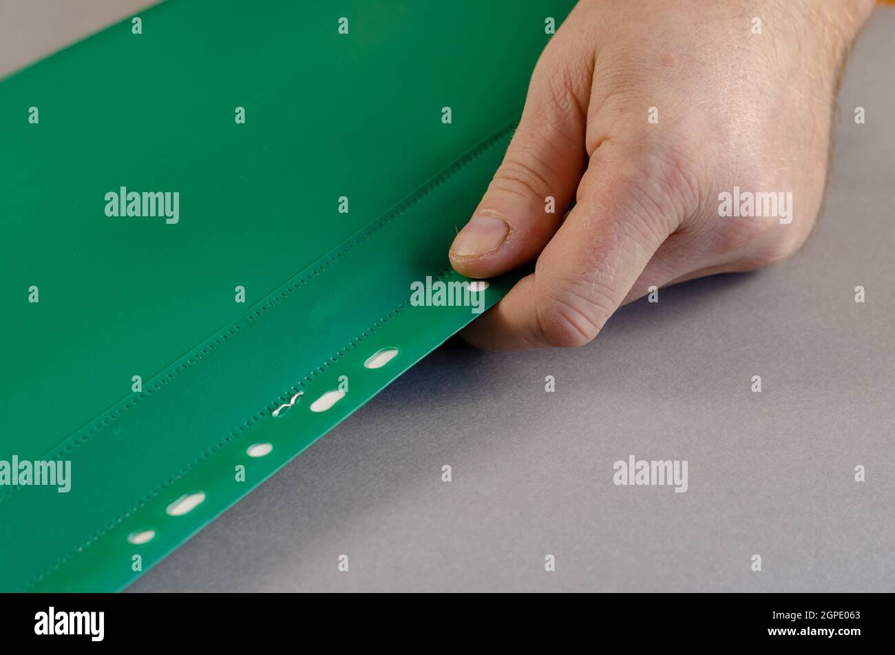 A hand with a green file folder on a gray surface. A grown man i Stock ...