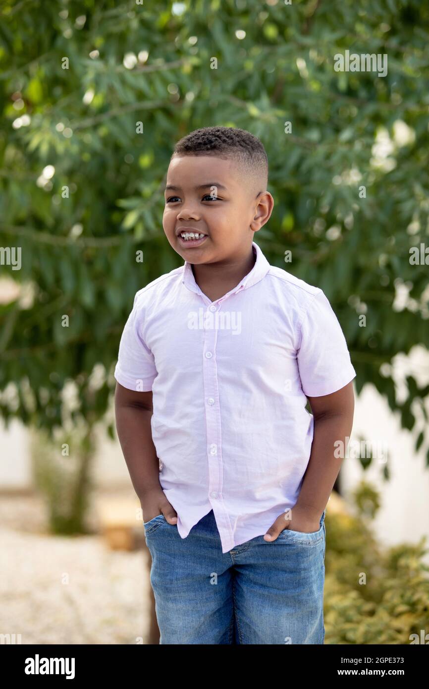 Adorable latin child in the garden with a beautiful green of background ...