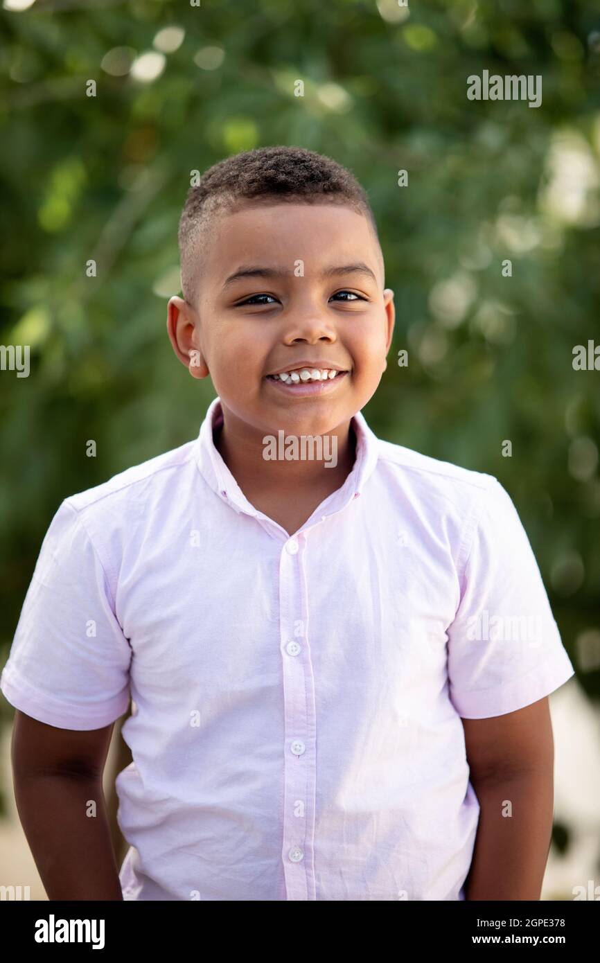 Adorable latin child in the garden with a beautiful green of background ...
